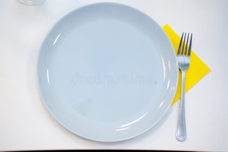 A Simple Dinner Plate with a Fork and a Yellow Napkin on the Table ...