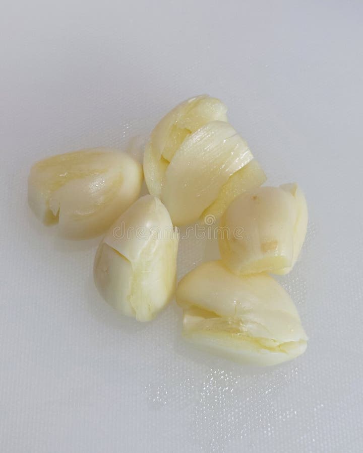Efficient Kitchen Prep: Peeled Garlic on White Plastic Chopping Board ...