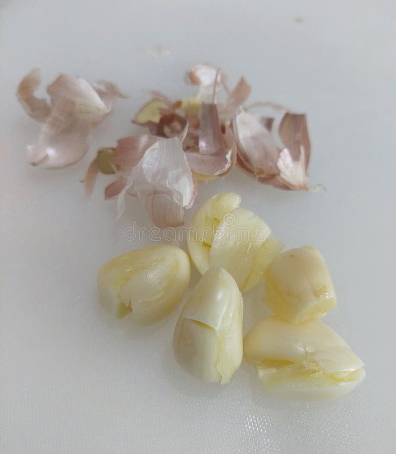 Efficient Kitchen Prep: Peeled Garlic on White Plastic Chopping Board ...