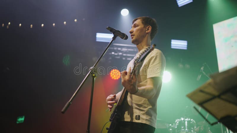 Singer with Guitar Performs on Lighted Stage. Guy Singing into ...