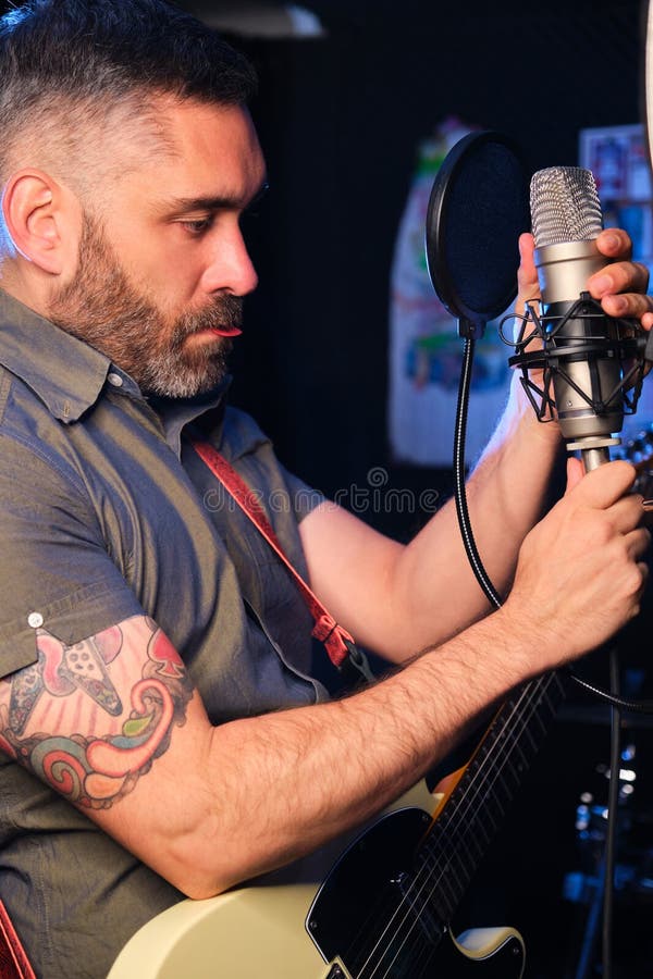 Singer and Guitarist Adjusting the Microphone before Recording at ...
