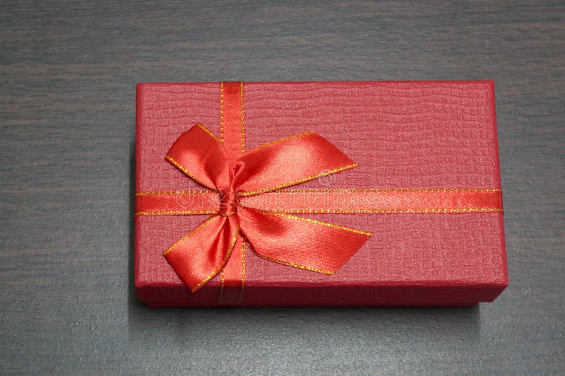 A Single Beautiful Red Gift Box with Red Bow Decorated on Black Wooden ...