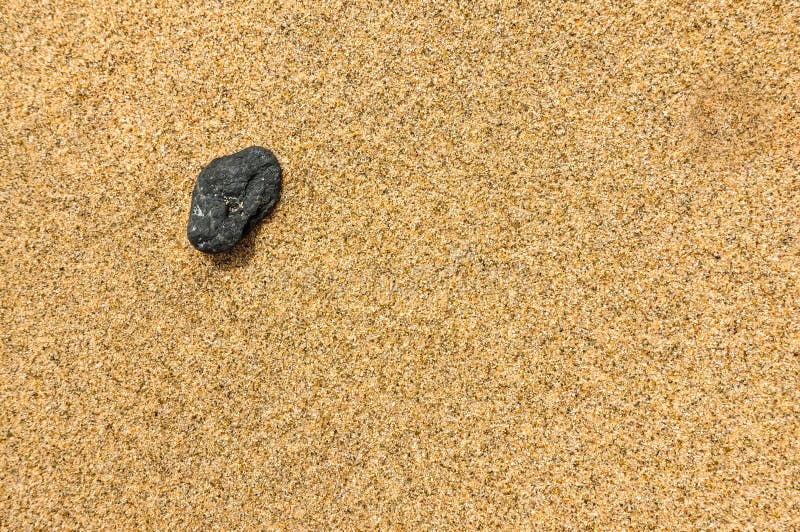 Single Black Stone in a Fine Sand at the Beach Stock Photo - Image of ...