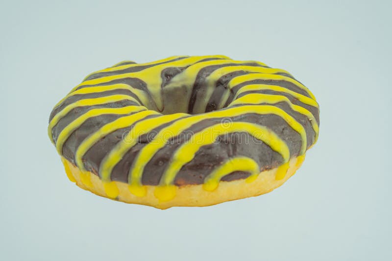 A Single, Circular, Glazed Donut with Yellow and Green Stripes is ...