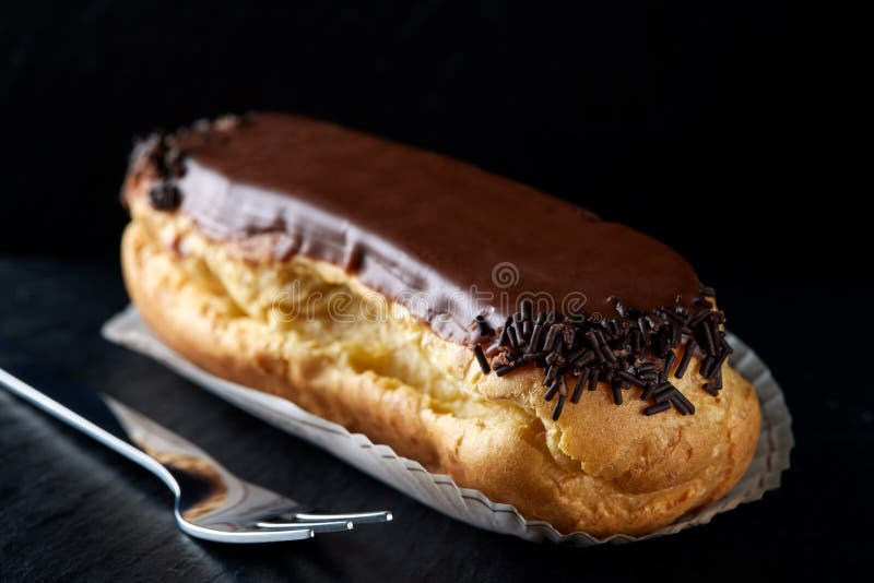 Single Eclair with Chocolate and a Fork on a Dark Slate Stock Image ...