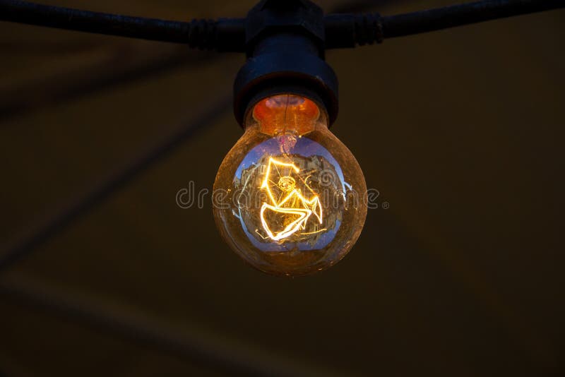 A Single Electric Light Bulb Lit Hanging from the Ceiling Stock Photo ...