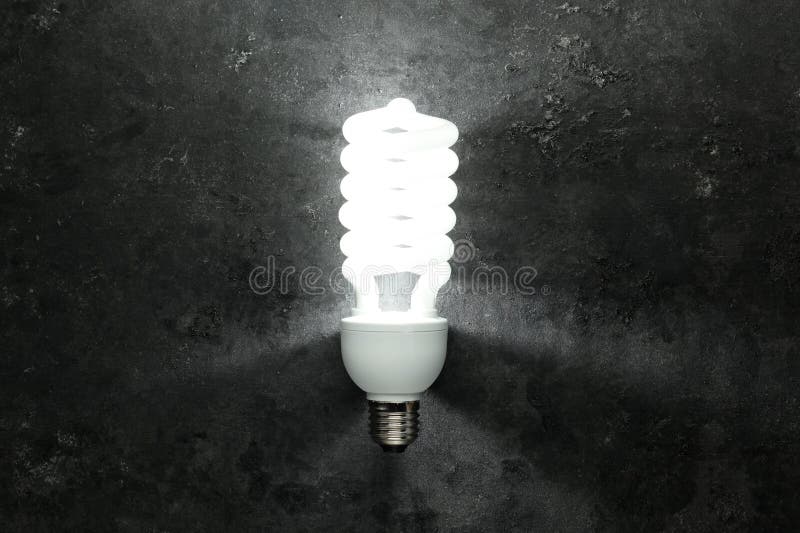 Single Energy Efficient Light Bulb Glowing Brightly in a Dark Room. New ...