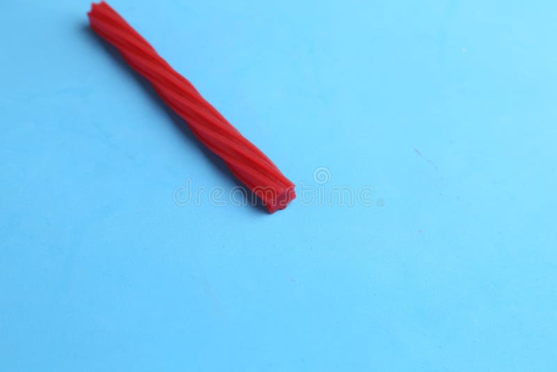 Single Long Red Twisted Candy on a Blue Background Stock Photo - Image ...