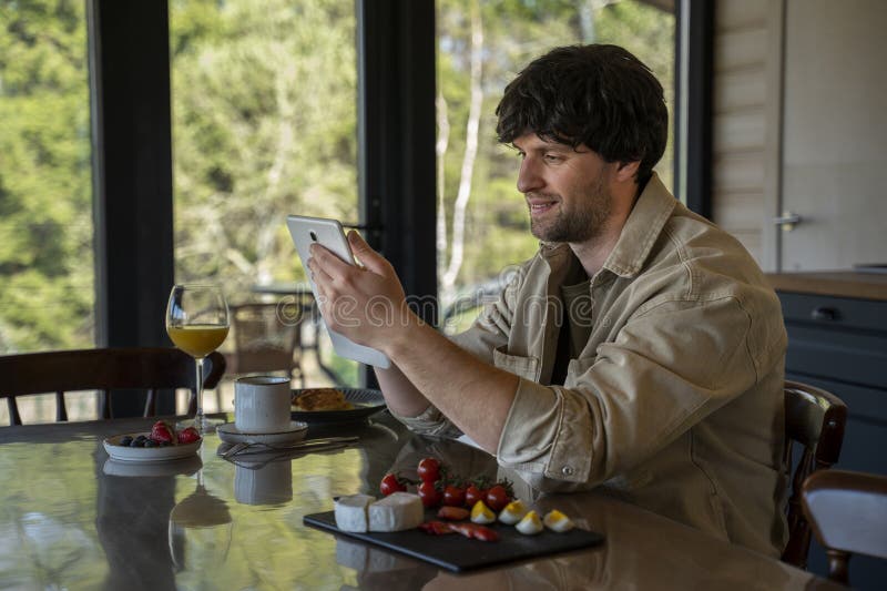 A Single Man Has Breakfast in the Kitchen, Working from Home.a Man Uses ...