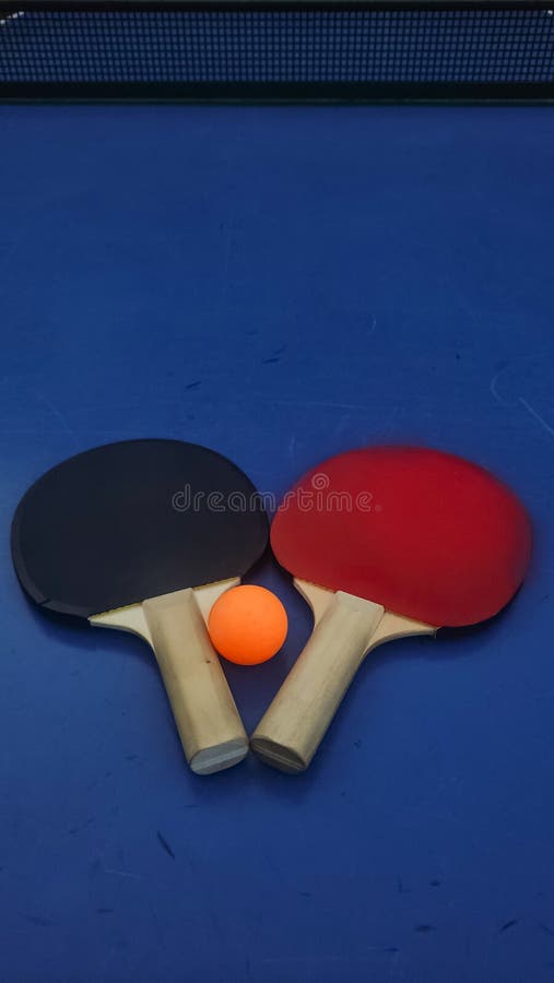 A Single Orange Ping Pong Ball Sits between Two Crossed Ping Pong ...