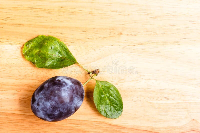 Single Plum Fruit with Green Leaves on Wooden Table Stock Image - Image ...