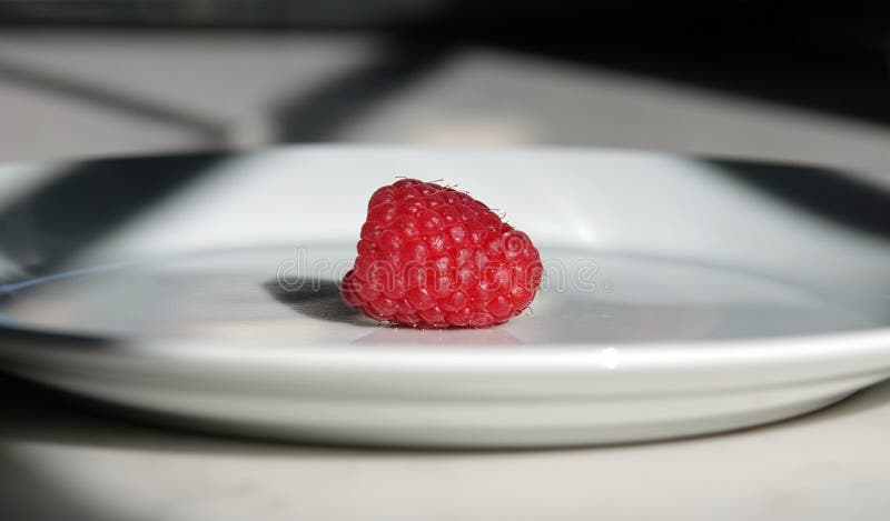 Single Raspberry on a Ceramic Plate in a Dark Kitchen Stock Photo ...