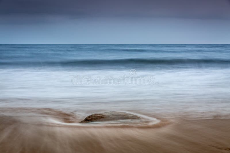 A Single Rock on the Beach As the Wave Backwash Returns To the Sea Over ...