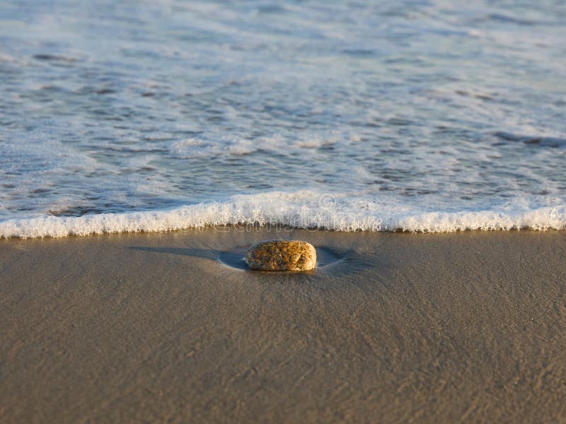 Single Rock in the Sand with Wave Approaching. Stock Image - Image of ...