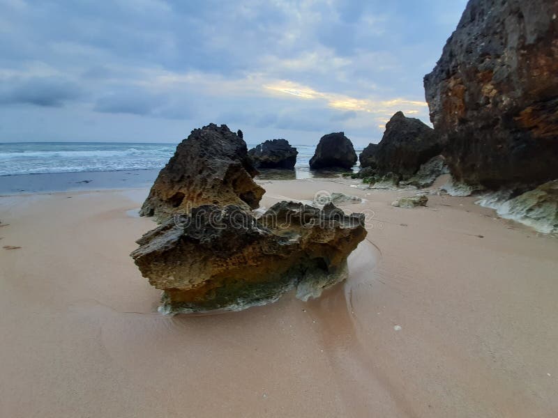 Single Rocks on a Sand Beach Against Blue Ocean and Cloud Sky at ...