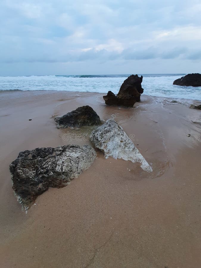 Single Rocks on a Sand Beach Against Blue Ocean and Cloud Sky at ...