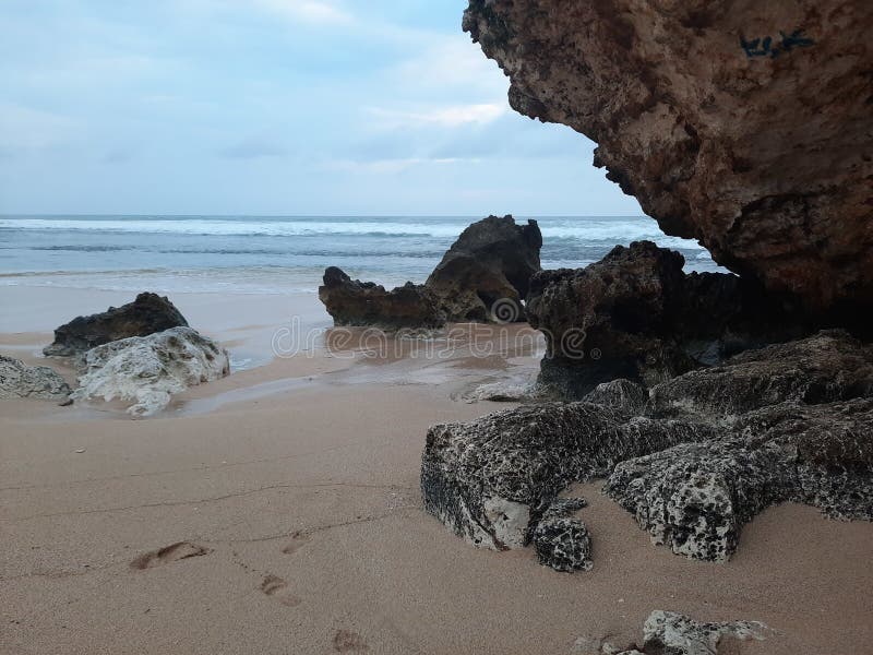 Single Rocks on a Sand Beach Against Blue Ocean and Cloud Sky at ...