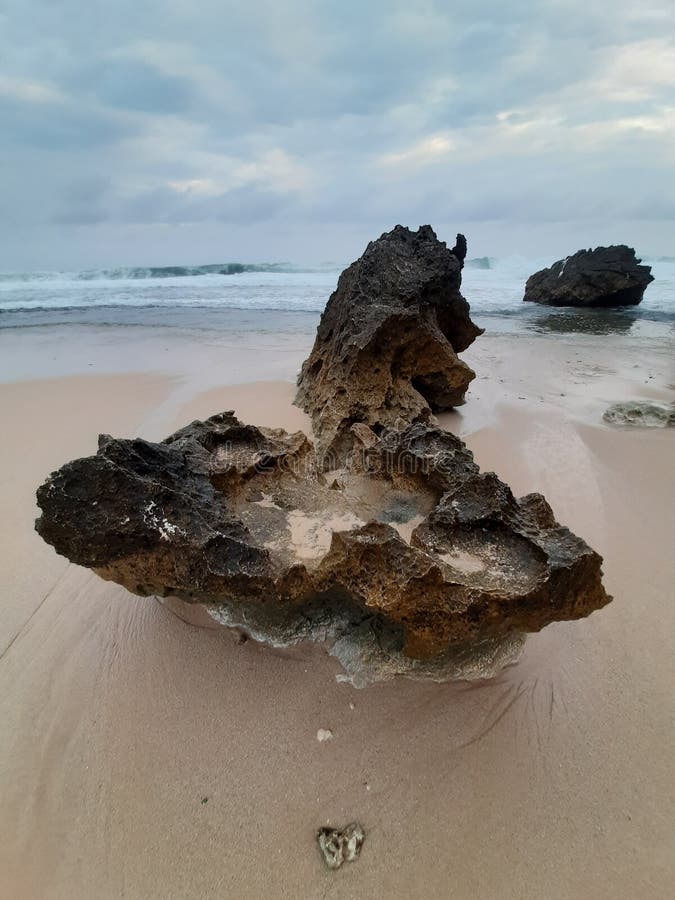 Single Rocks on a Sand Beach Against Blue Ocean and Cloud Sky at ...