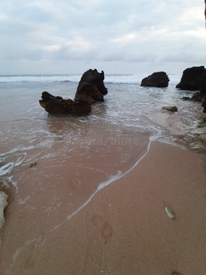 Single Rocks on a Sand Beach Against Blue Ocean and Cloud Sky at ...