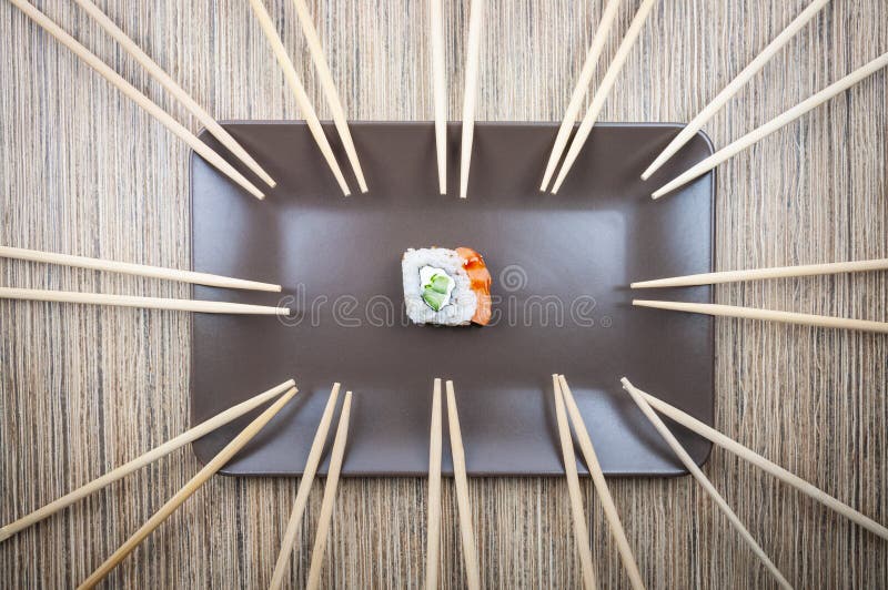 Single Sushi Roll in Plate with Many of Chopsticks on Wooden Table ...