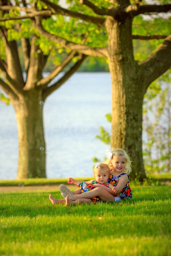 Sisters sitting outside stock photo. Image of happy, grass - 73096608