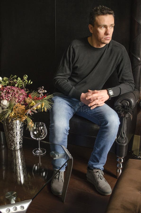 Sitting Man in a Black Sweater and Blue Jeans Stock Image - Image of ...