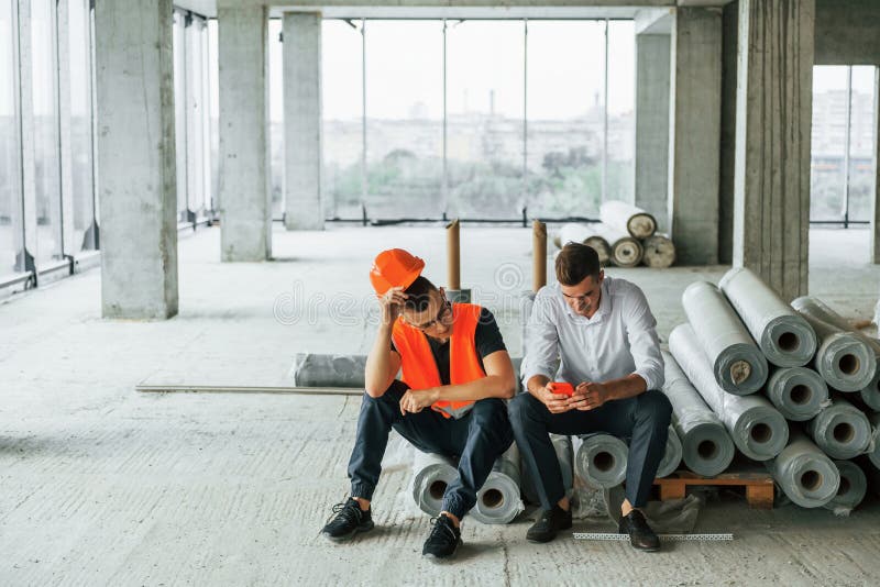 Sitting on the Materials. Man in Suit and Handyman in Orange Protective ...