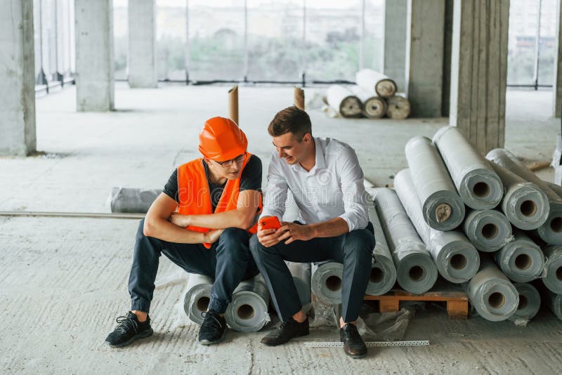 Sitting on the Materials. Man in Suit and Handyman in Orange Protective ...