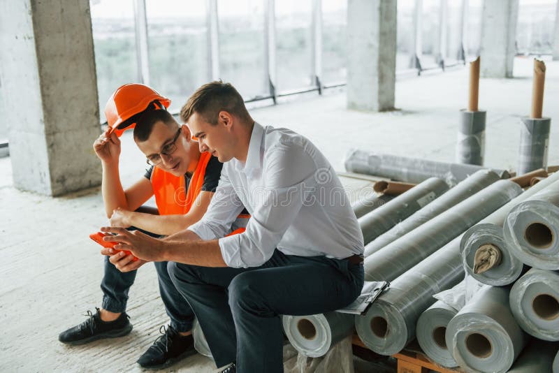 Sitting on the Materials. Man in Suit and Handyman in Orange Protective ...