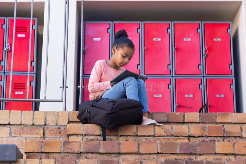 Sitting on Steps, African American Girl Reading Tablet in Front of ...