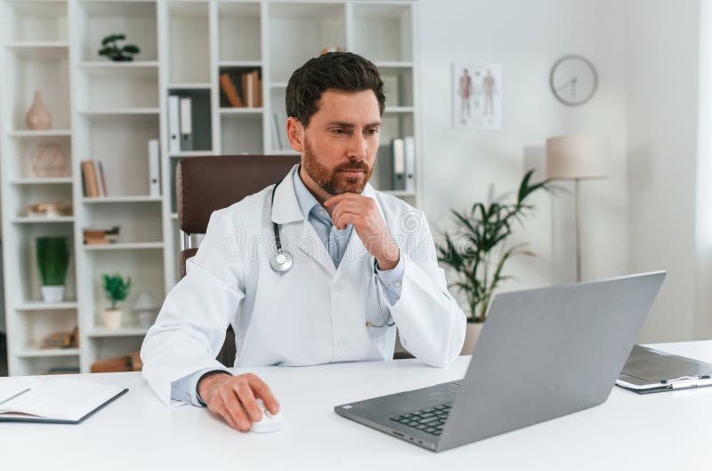 Sitting by a Table. Doctor in Formal Clothes is Working in the Cabinet ...
