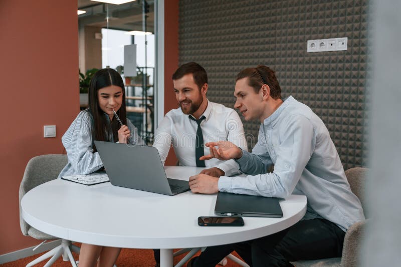 Sitting, Talking, Using Laptop. Office Workers are Indoors by the Table ... Sitting, Talking, Using Laptop. Office Workers are Indoors by the Table ...