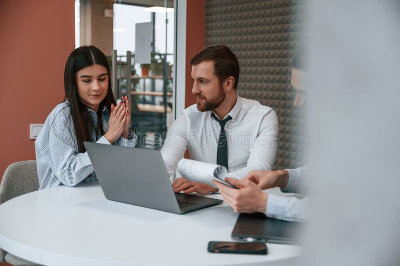 Sitting, Talking, Using Laptop. Office Workers are Indoors by the Table ...