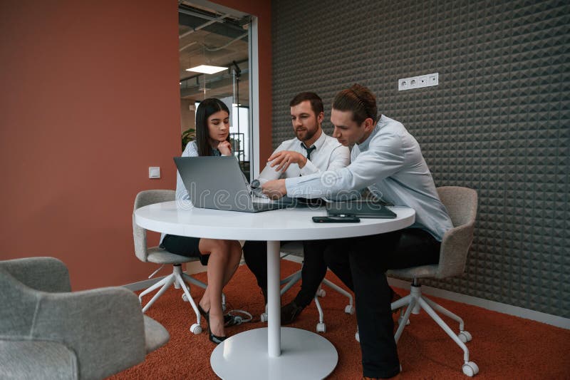 Sitting, Talking, Using Laptop. Office Workers are Indoors by the Table ...