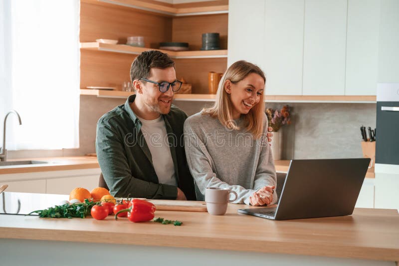 Sitting, Using Laptop. Young Couple is on the Kitchen Together Stock ...