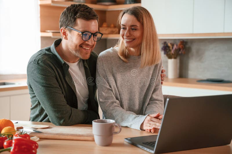 Sitting, Using Laptop. Young Couple is on the Kitchen Together Stock ...