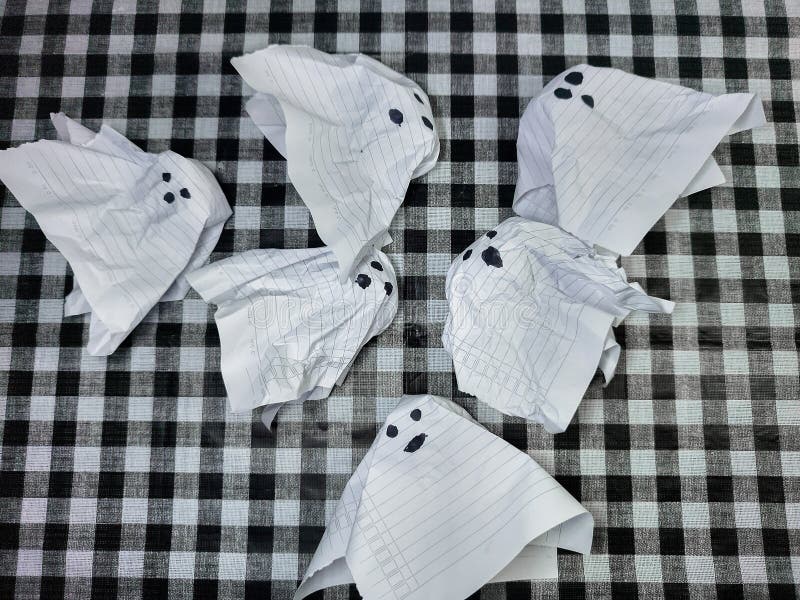 Six Crumpled Paper Ghosts with Drawn Faces Form a Circle on a Black and ...