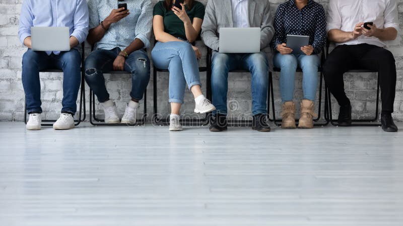 Six Multiethnic Young People Sit in Queue Holding Electronic Devices ...