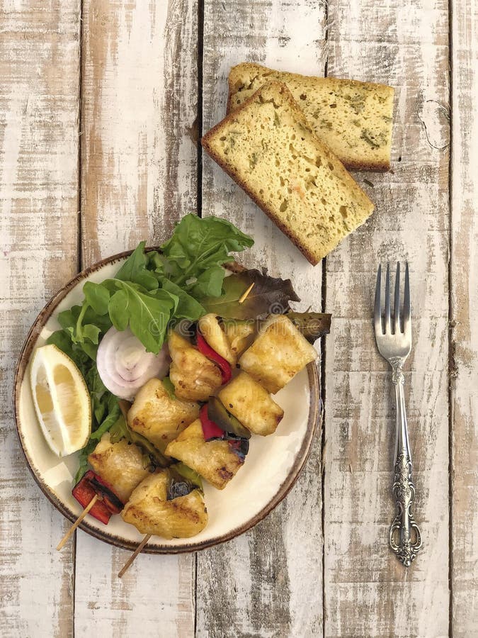 Skewed Sole Fish Served with Salad and Corn Bread on Table Stock Photo ...