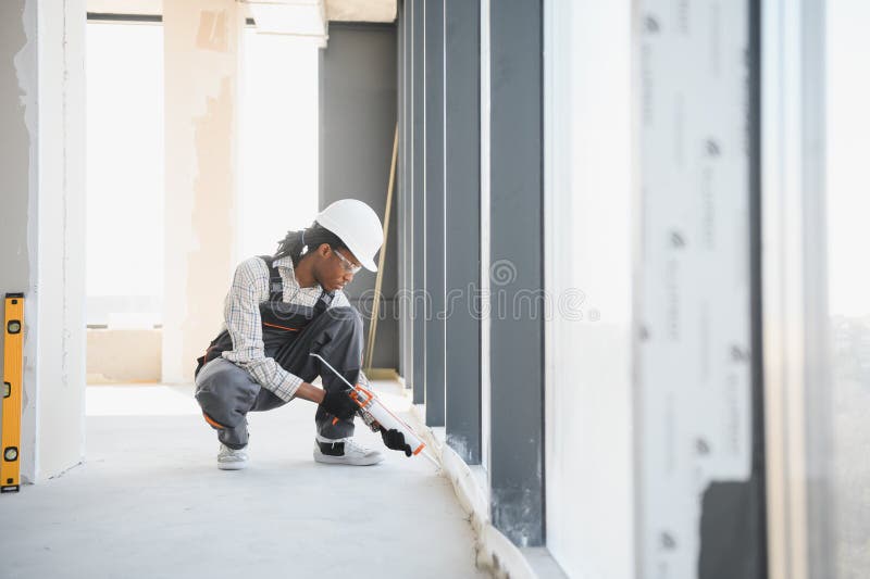 Construction Worker Applying Sealant To Window Frame in Building Under ...