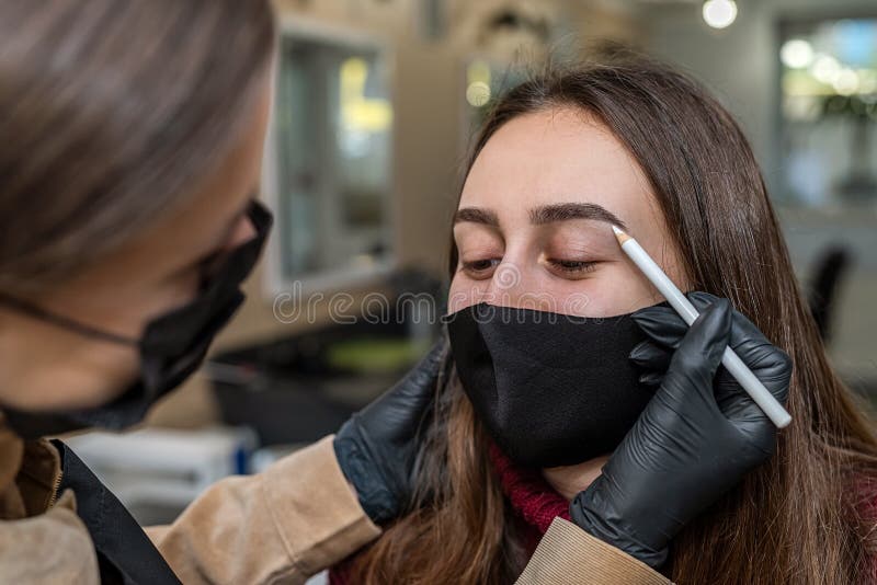 Skilled Eyebrow Master Draws Eyebrows of a Client in a Mask with a ...