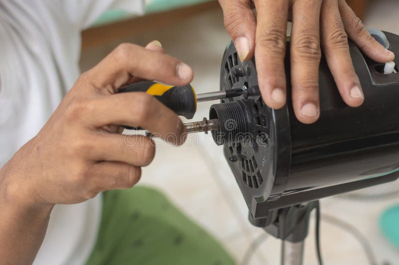 A Skilled Technician is Focused on Fixing a Motor of an Electric Fan ...
