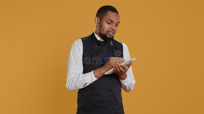Skilled Waiter with Apron Takes Meal Orders from Clients on a Notebook ...