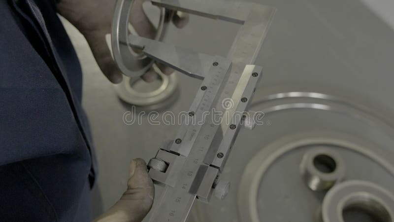 A Skilled Worker in Blue Measures the Dimensions of a Part Using a ...