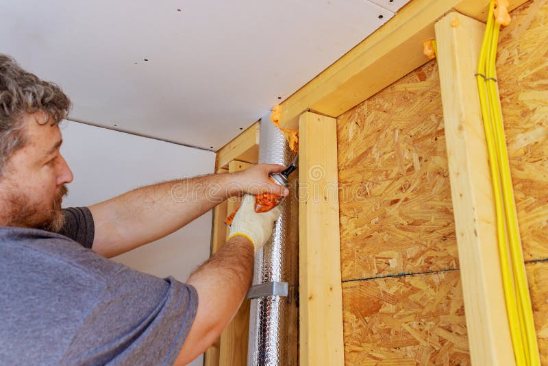 Skilled Worker Installing Insulation in Wooden Framework Inside a Residential Building during ...