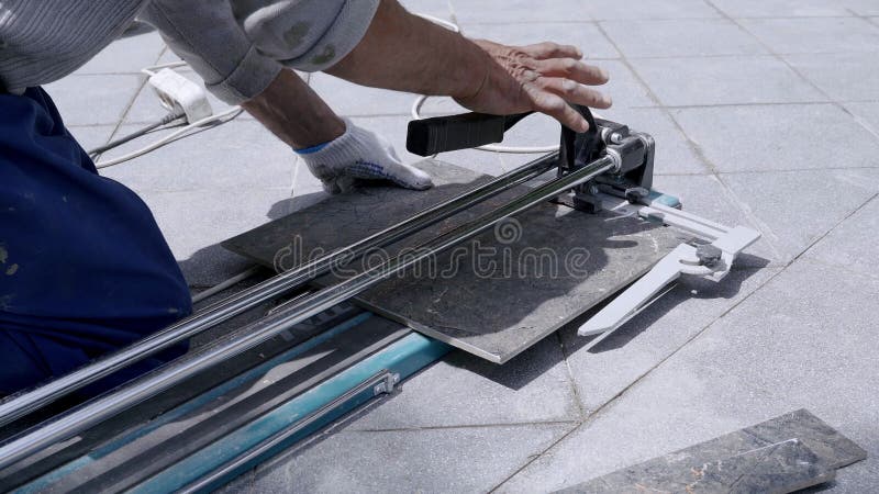 Skilled Worker Using a Cutting Tool To Shape Tiles on a Construction ...