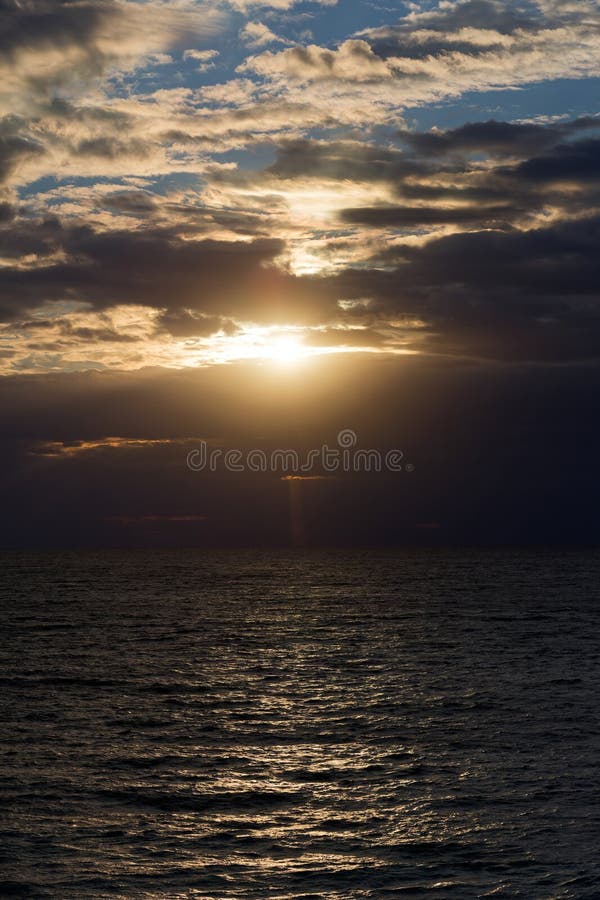 The Sky is Dark and Cloudy, with a Sun Setting in the Distance Stock ...