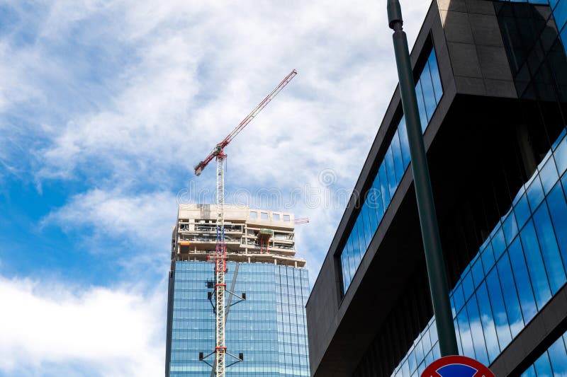 Skyscraper Under Construction with a Crane on a Blue Sky Background ...