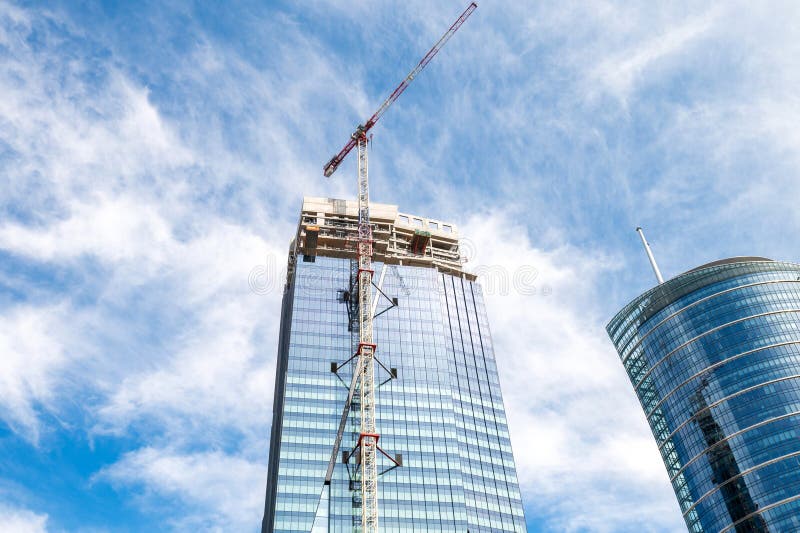 Skyscraper Under Construction with a Crane on a Blue Sky Background ...