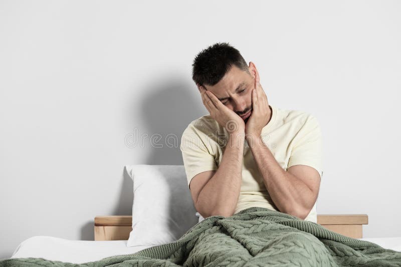 Sleep Deprived Man Sitting on Bed at Home Stock Photo - Image of ...